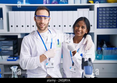 Interracial couple working at scientist laboratory smiling happy and ...