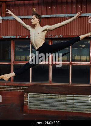 Concentrated young blond slender ballet dancer in black leotard and ...