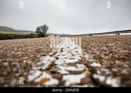 Low level view of a rural asphalt road, appearing deserted ascending a ...