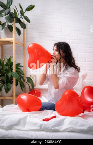 Happy couple with red balloon sitting at home on Valentine's Day Stock ...