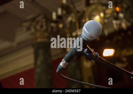 Microphone on stage with blurred audience in background. A close-up of ...