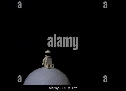 toy astronaut falling into the void in the middle of the black space ...