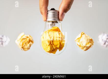 Close up photo of crumbled colorful paper and light bulb in the same ...
