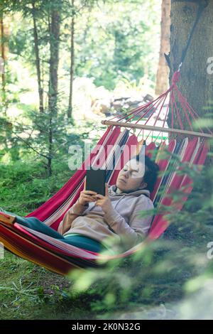 woman laying down in hammock in the forest tent on background copy ...