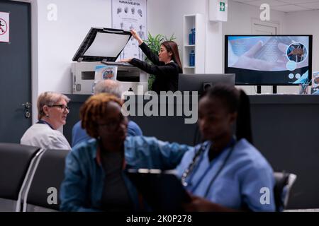 Secretary using copy printer at reception counter to make report papers ...