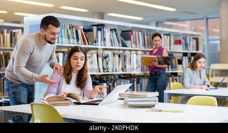 Man recommending books to woman in public library Stock Photo - Alamy
