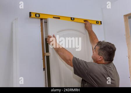 An employee leveling the interior doors of a new house during the ...