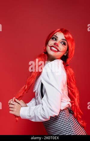 smiling woman with bright ponytails and halloween makeup holding jack o ...