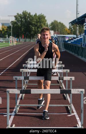 Young man athlete runnner running hurdles at the stadium outdoors Stock ...