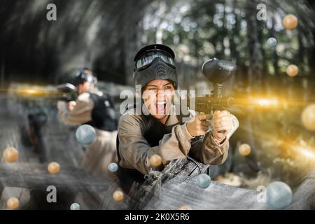 Happy girl targeting shooting with paintball marker Stock Photo - Alamy