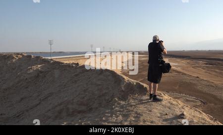 A photographer takes photos from the salt wall barrier along the border ...
