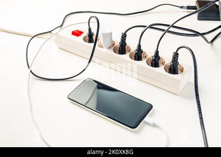 Many chargers plugged into multiple socket Stock Photo - Alamy