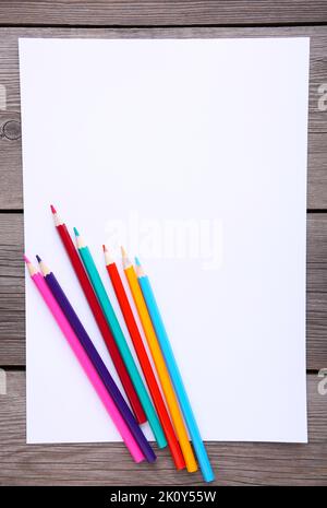 Many different colored pencils with white paper on grey wooden ...