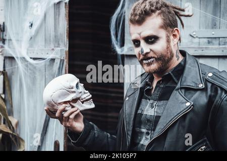 Scary man with dreadlocks looking at skull. Celebrating halloween ...