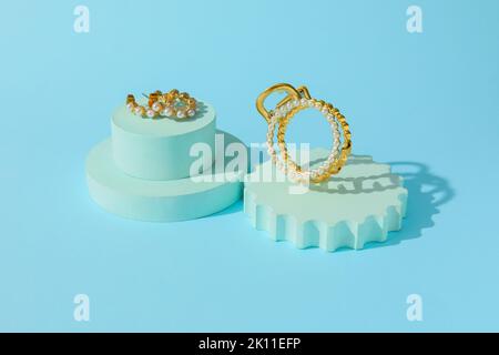 Showcase pedestals with stylish accessories on pink background, closeup ...