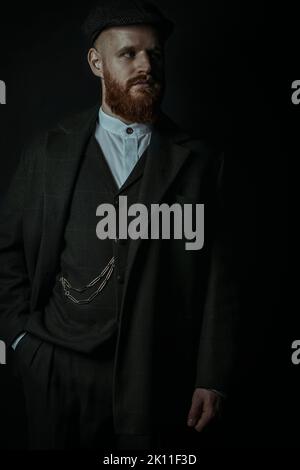 A working class Victorian man with red hair and beard against a black ...