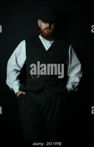 A working class Victorian man with red hair and beard against a black ...
