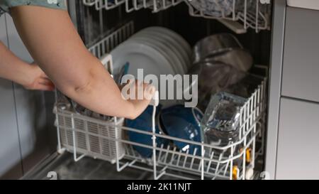 Dishwasher. hands sort clean dishes from the dishwasher. Plates, forks ...