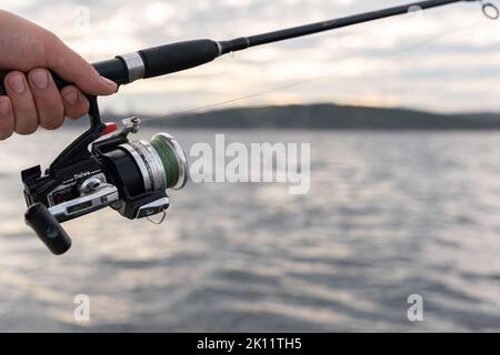 Fishing rod wheel close up, man fishing with a beautiful sunrise behind ...