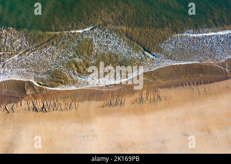 A beautiful shot of sea waves crashing on a beach surrounded by cliffs ...