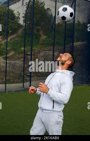 Sportsman juggling soccer ball on stadium at sunny day. Young man ...