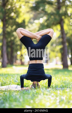 Woman doing headstand pose and lotus position on a yoga mat while ...