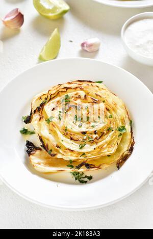 Roasted cabbage steaks on plate over white background. Top view, flat ...