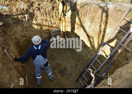 Worker manually loads stones into an excavator's shovel during the ...