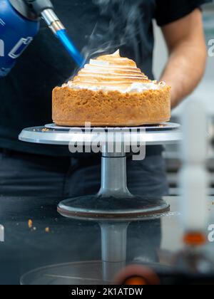 baker using a pastry burner flame torch on a meringue cake Stock Photo ...