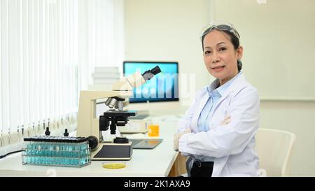 Middle age woman wearing scientist uniform measuring liquid at ...
