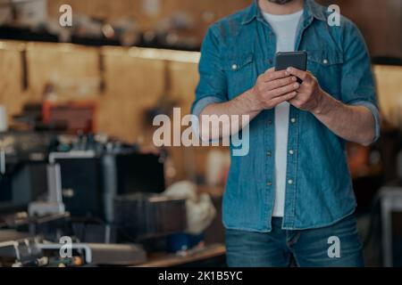 Unrecognizable repairman with a screwdriver standing on own workshop ...
