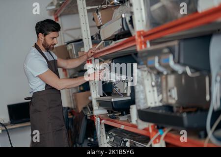 Man worker in uniform inspecting coffee machine in own workshop Stock ...