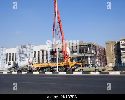 A concrete pump truck and a concrete mixer truck at a New York City construction site. The ...
