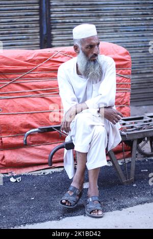 A vertical shot of a Pakistani male with a beard in a market doing ...