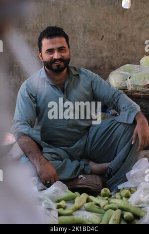 A vertical shot of a Pakistani male with a beard in a market selling ...