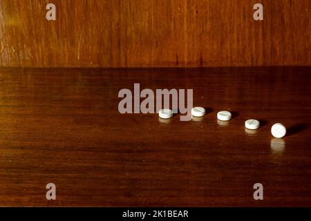 Simple pile of white pills, medicines, pills stacked on brown ...