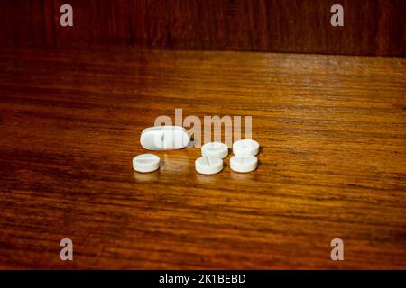 Simple pile of white pills, medicines, pills stacked on brown ...