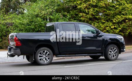 black toyota hilux SUV car driving along an unmade stone track road ...