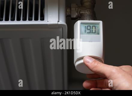 Hand turns down the temperature to 19 degrees Celsius on a electronic ...