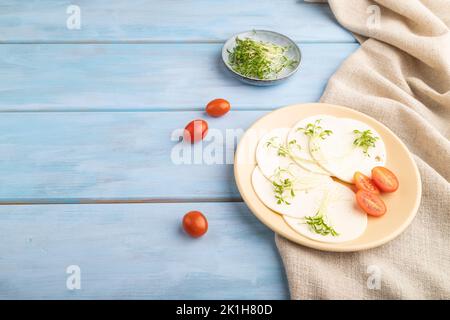 White cheese with tomatoes and cilantro microgreen on blue wooden ...