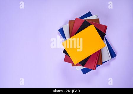 Stack of colorful books on purple background Stock Photo - Alamy