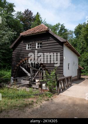 Old water mill with undershot waterwheel and red brick chimney on the ...