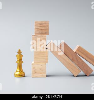 wooden Blocks or Dominoes falling to golden Chess King figure. Business ...
