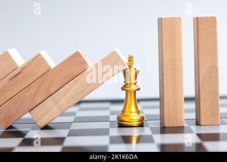 wooden Blocks or Dominoes falling to golden Chess King figure. Business ...