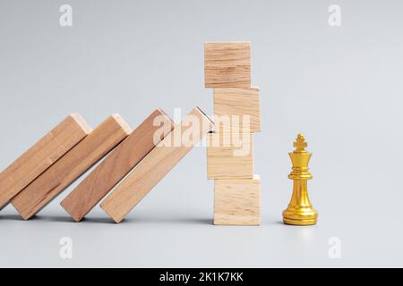 wooden Blocks or Dominoes falling to golden Chess King figure. Business ...
