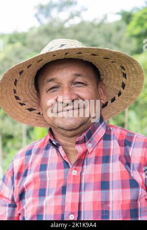 Young latin man wearing farmer hat and apron looking unhappy and angry ...