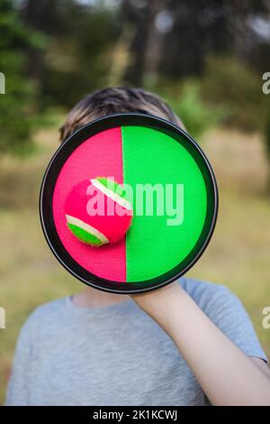 Portrait of a boy holding a velcro sticky ball game in front of his ...