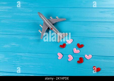 Top view of toy passenger boeing plane with red hearts. Blue wooden ...