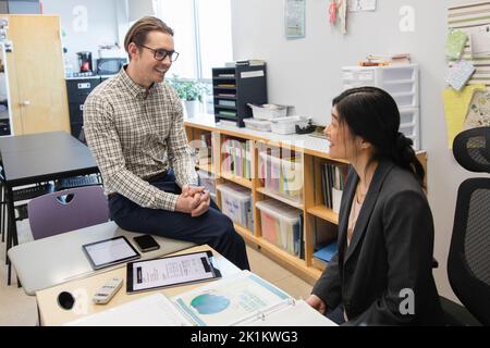Two smiling teachers talking in corridor in high school Stock Photo - Alamy