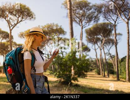 Enterprising and happy woman explores in the forest with her phone and ...